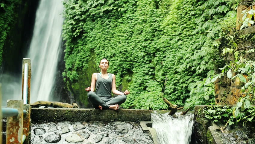Woman Doing Sitting Meditation At Waterfall In The Tropics Stock ...